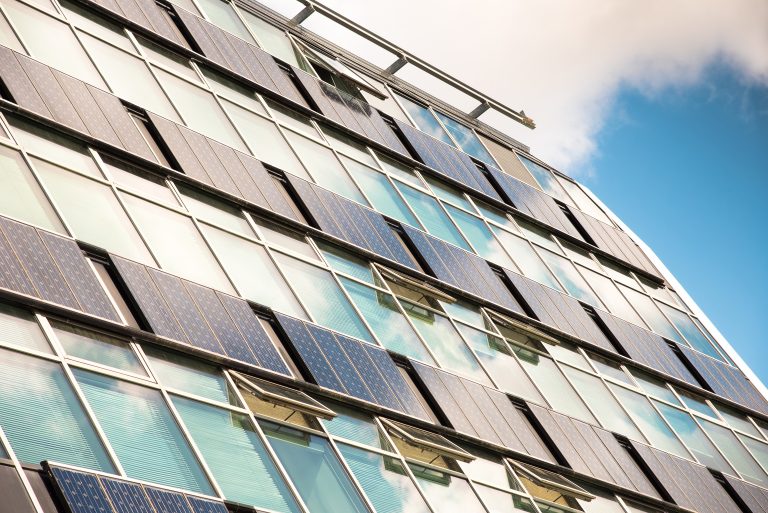 solar panels on modern glass facade with cloud reflections